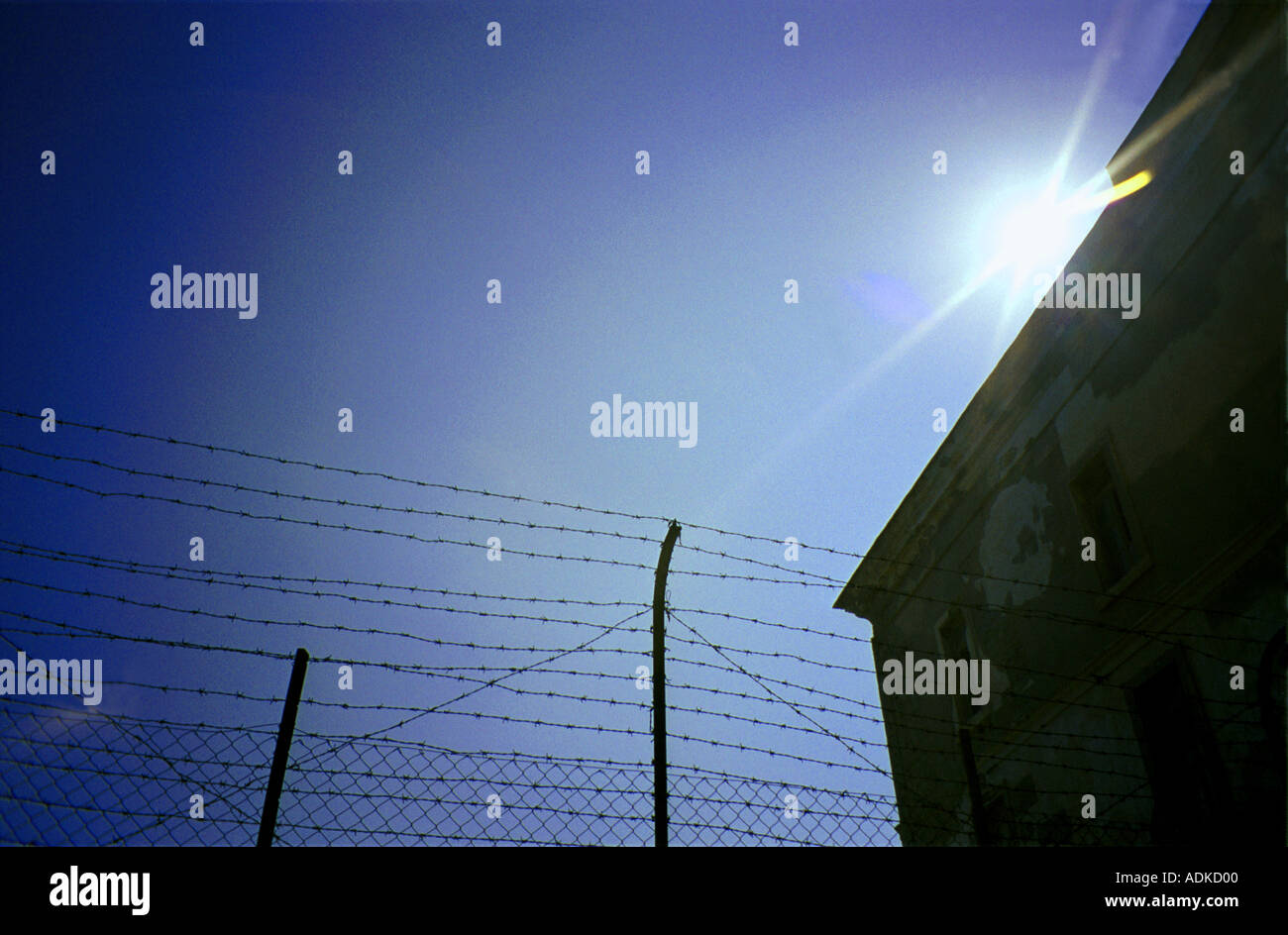 sun over building and barbed wire fence Stock Photo - Alamy