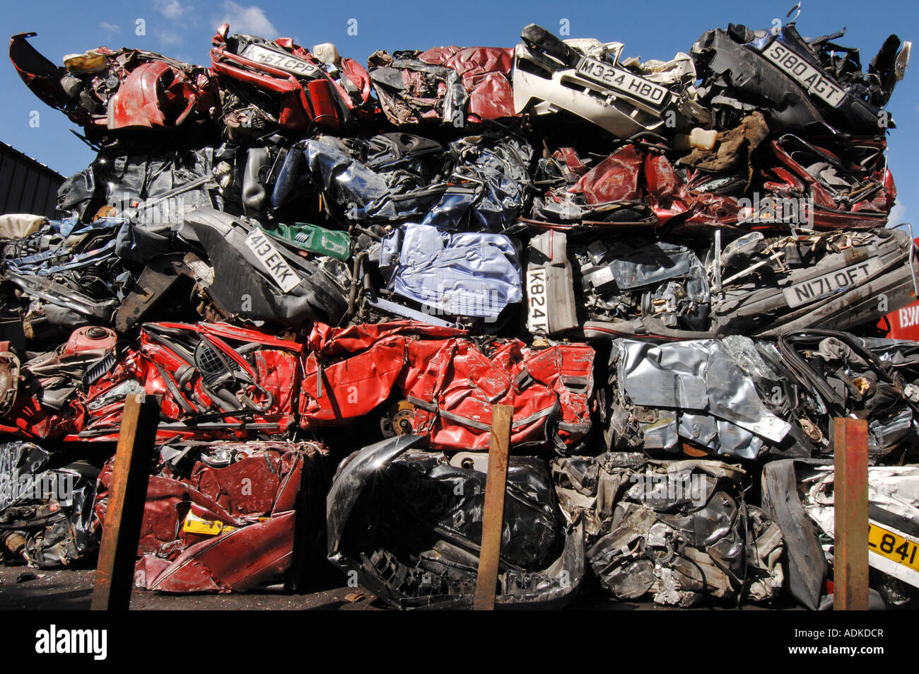 Cubes of crushed cars stand in a huge pile at a car recycling and ...