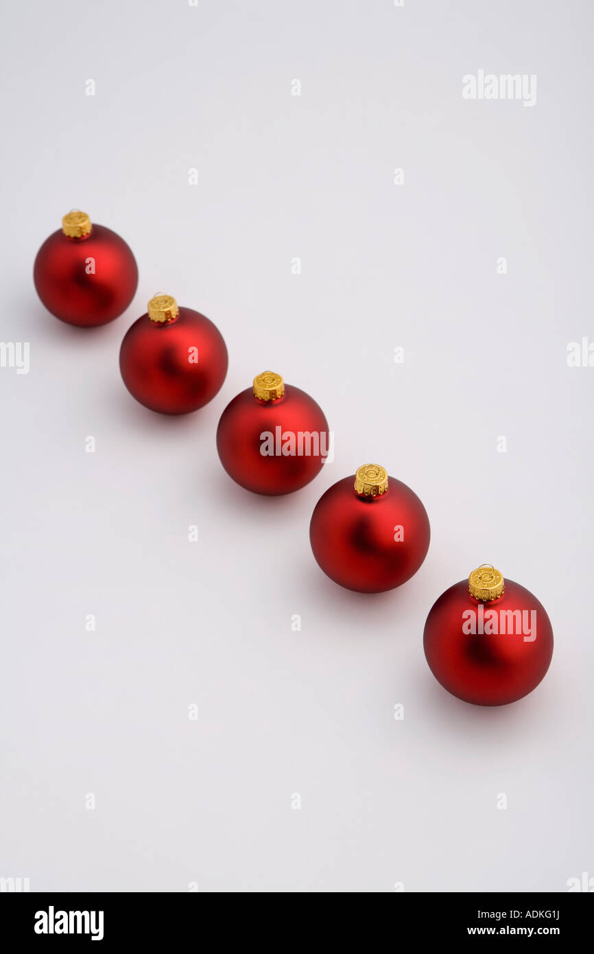 Four red Christmas balls in a diagonal line on white background studio ...