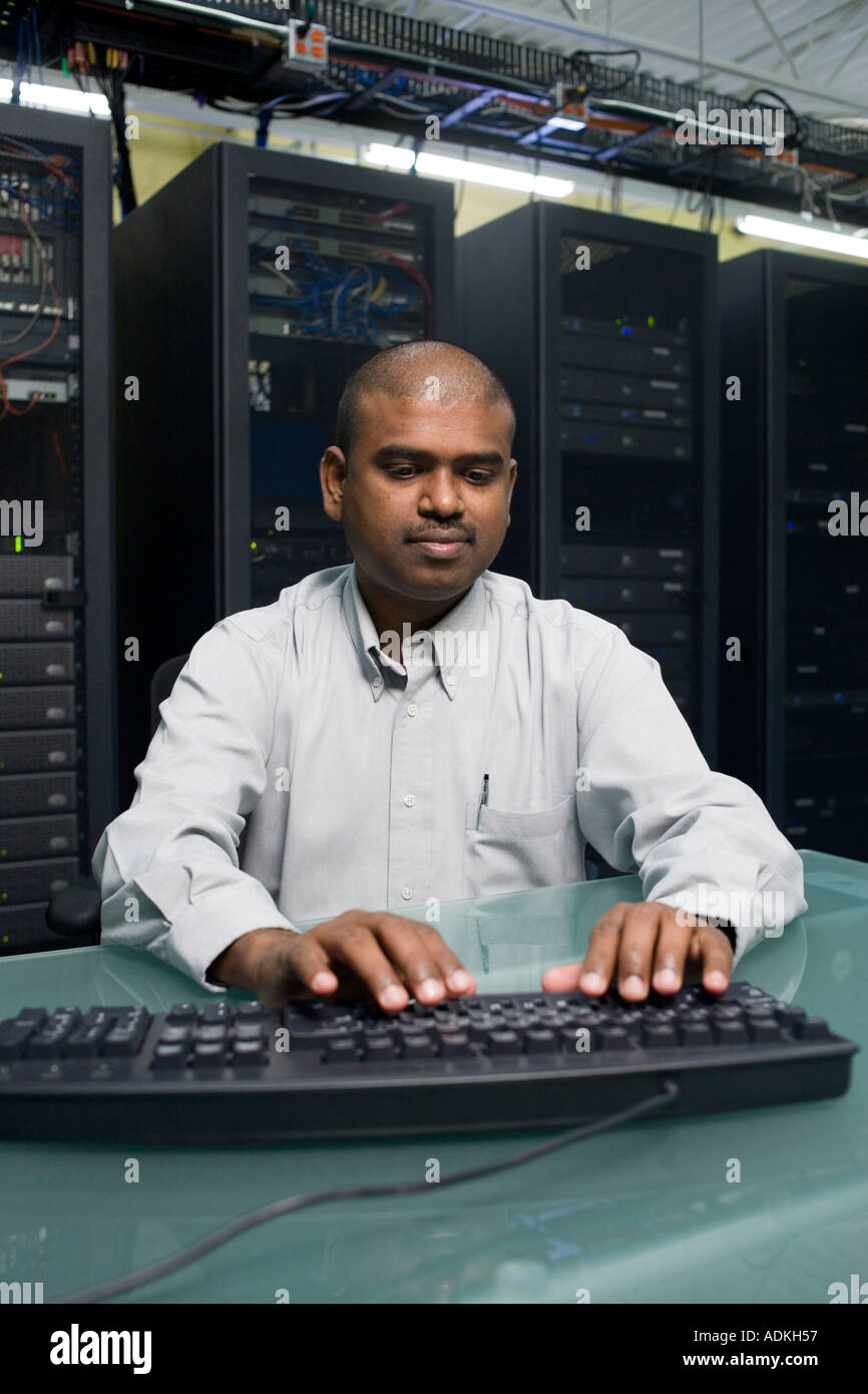 Technician working on a computer sitting in a server room Stock Photo ...