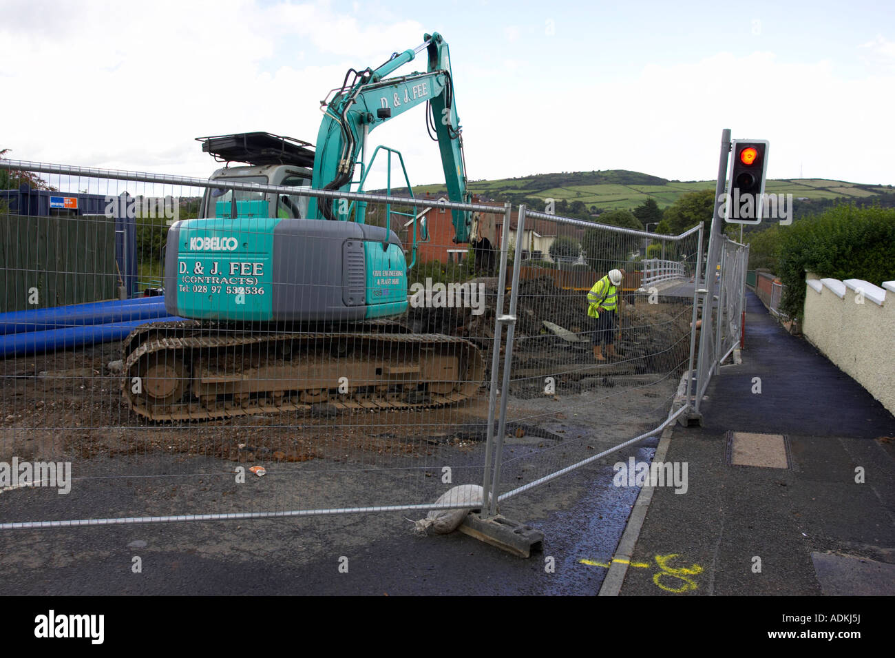 Metal fence around excavator carrying out repairs to roadway with ...