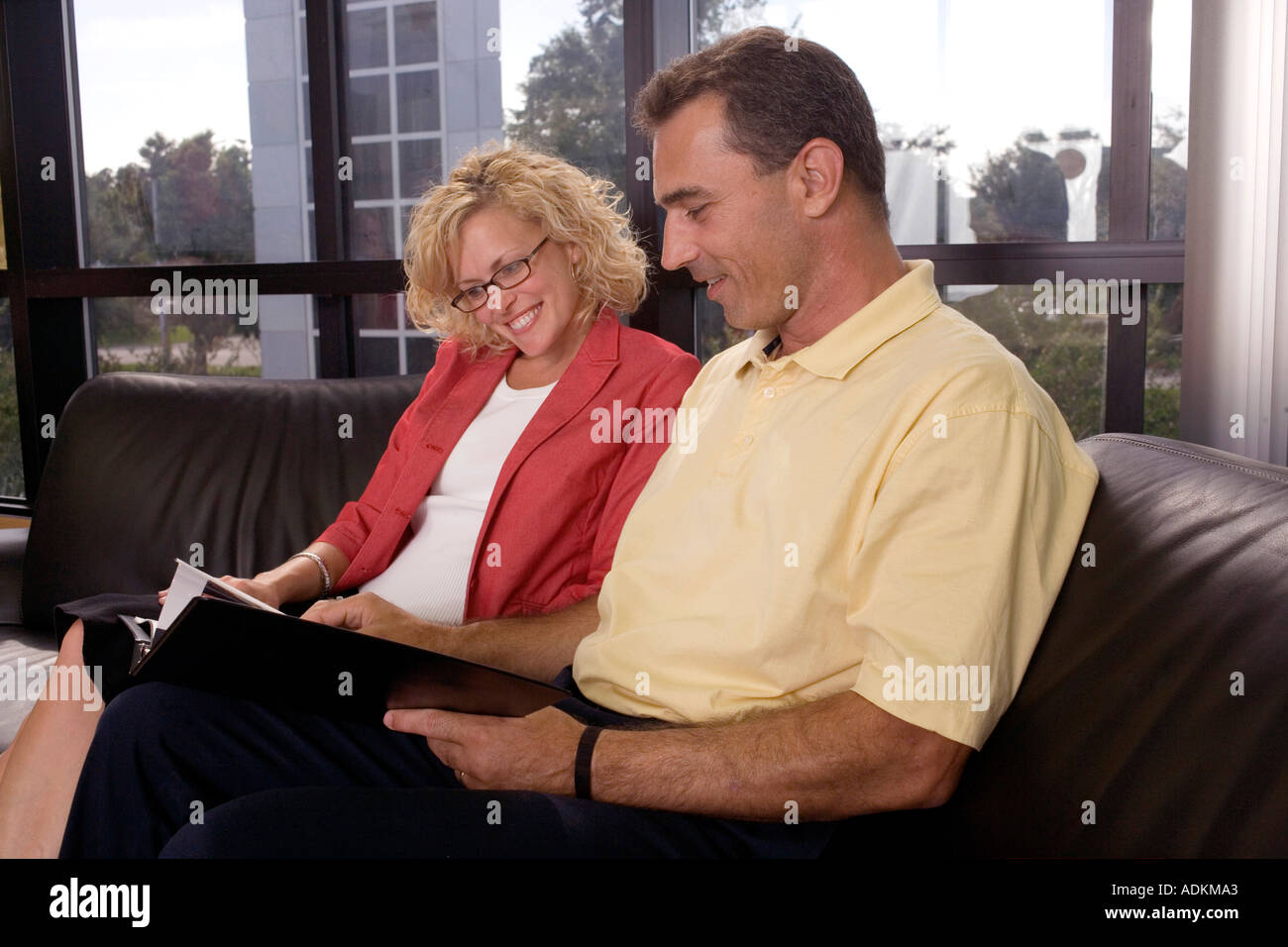 Side profile of a businessman and a businesswoman sitting on a couch ...