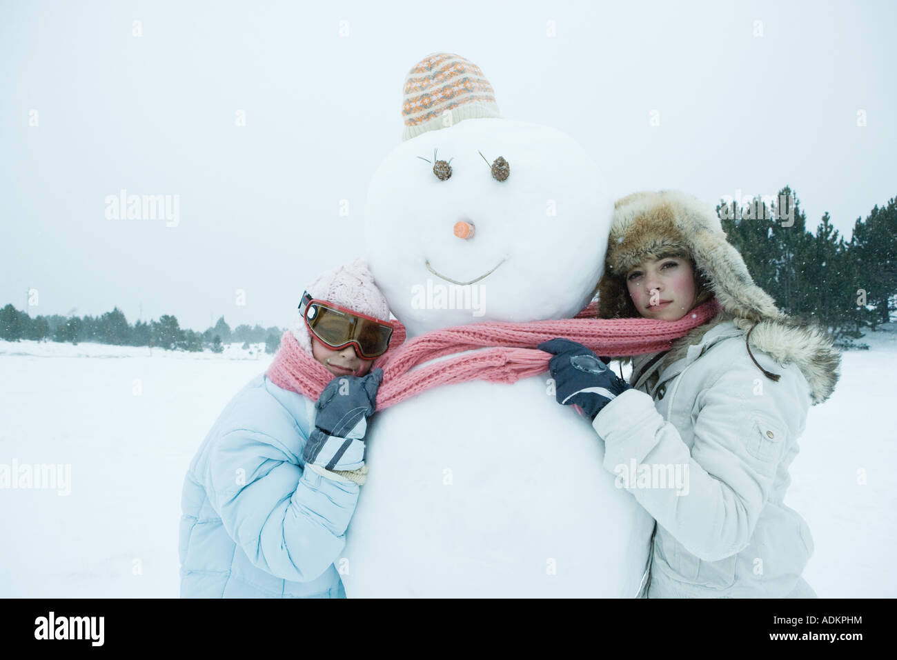 Two friends hugging snowman Stock Photo - Alamy