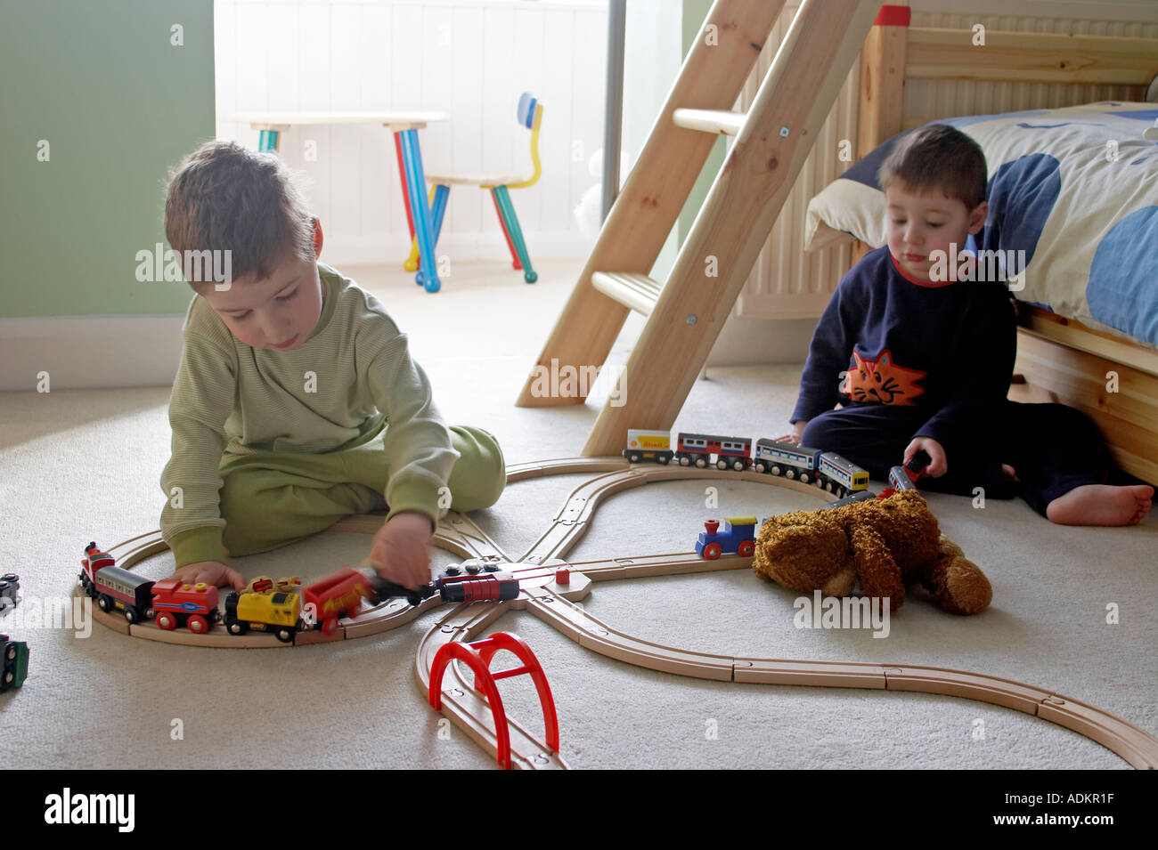 Two young boys playing with train set and toys in their bedroom Stock ...