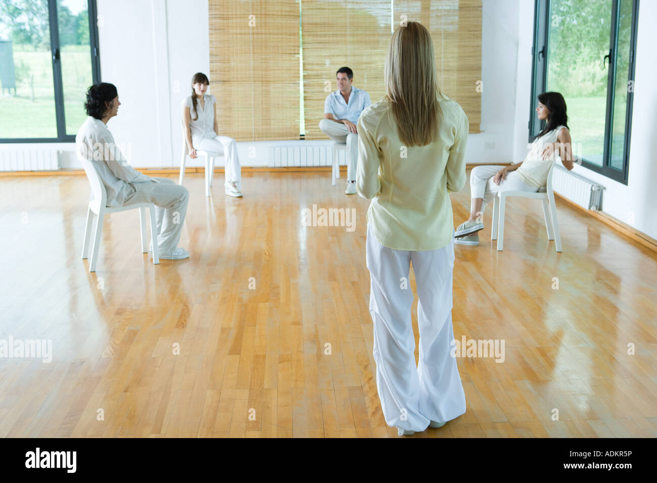 Group therapy, adults sitting in chairs, one woman standing in ...