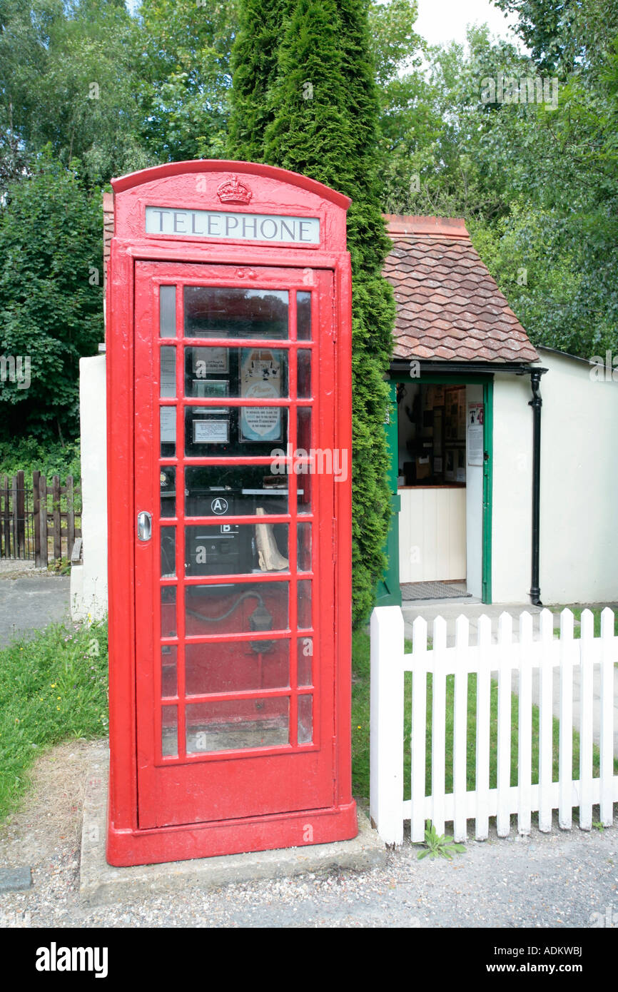 Traditional red English public phone box beside white picket fence at ...