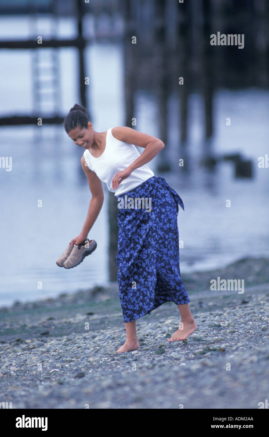 African American Woman Walking Barefoot On A Rocky Beach Stock Photo ...