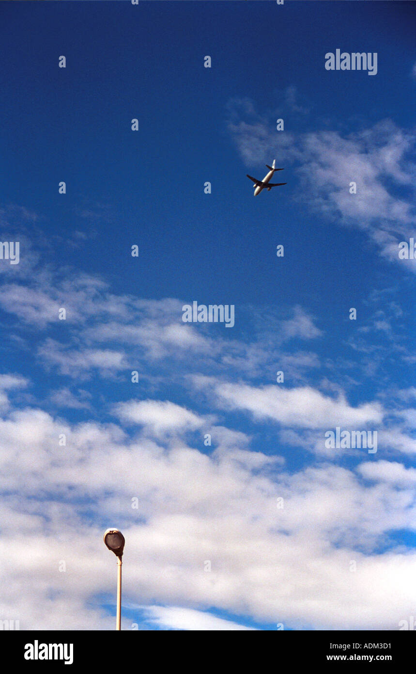 plane moving across sky with clouds and lamp post Stock Photo - Alamy