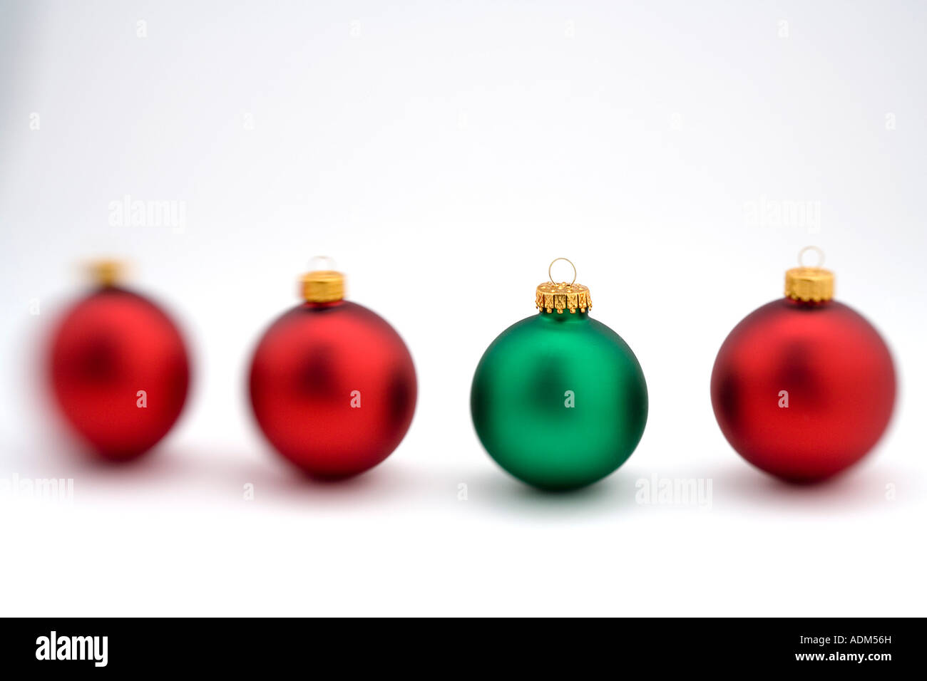 One green Christmas tree bulb ornament in row with three red bulbs ...