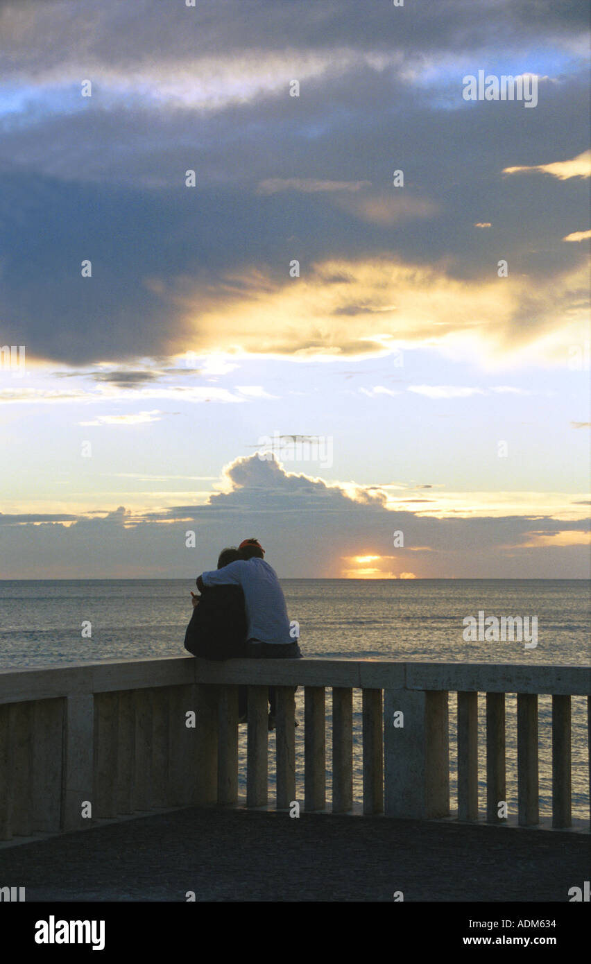 Couple watching sunset from a pier wall promenade Stock Photo - Alamy