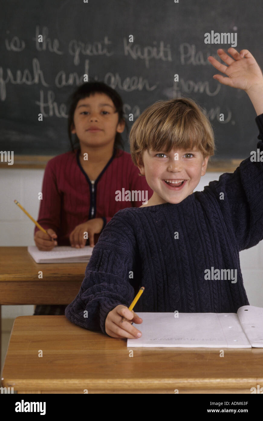 Excited young elementary aged boy raising his hand to answer a question ...