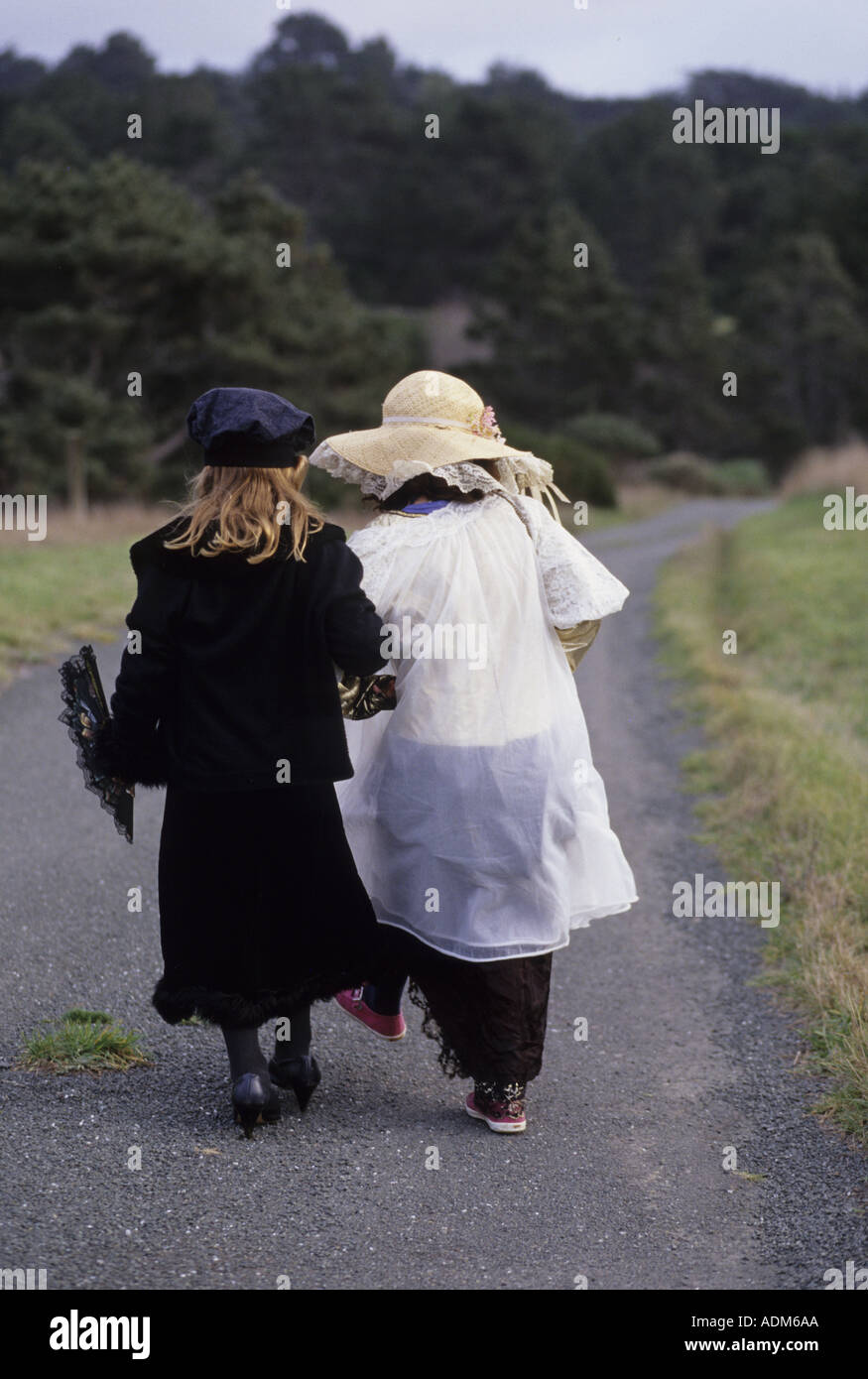 View from behind of two little girls walking down road in dress-up ...