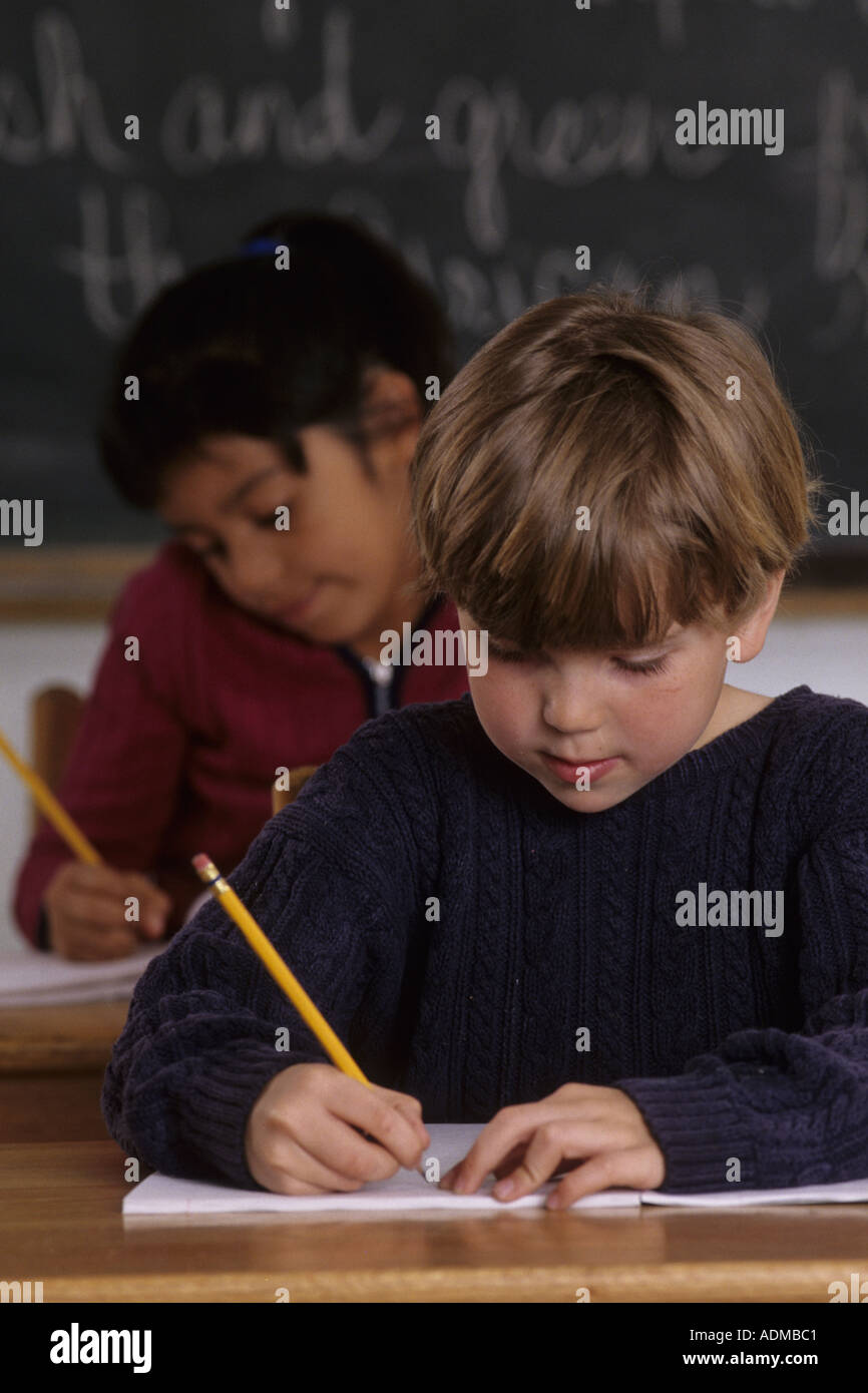 Young elementary aged boy working on his work in class Stock Photo - Alamy