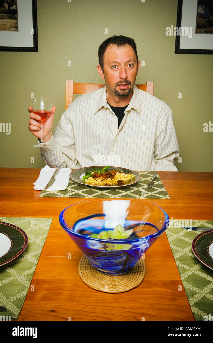 Portrait of a mid 40 s anebriated man drinking wine and eating dinner ...