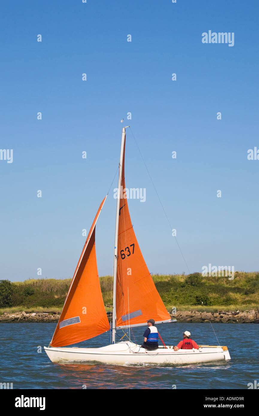 A red sailed small sailing boat on the river Medway at Upnor Kent UK ...