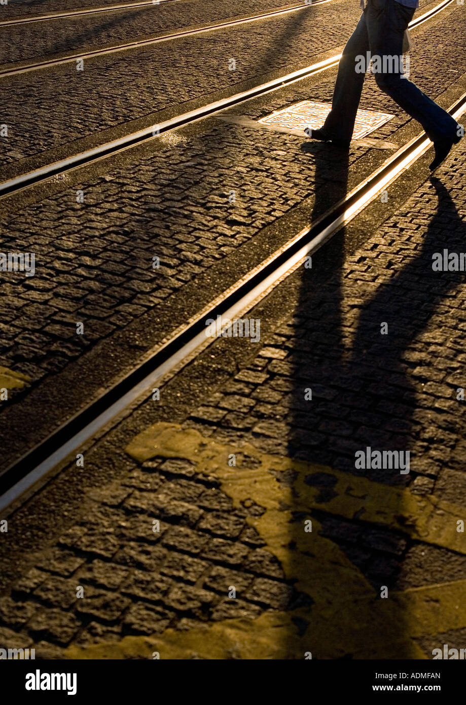 Pedestrian shadow over cobblestone street with train track Stock Photo ...