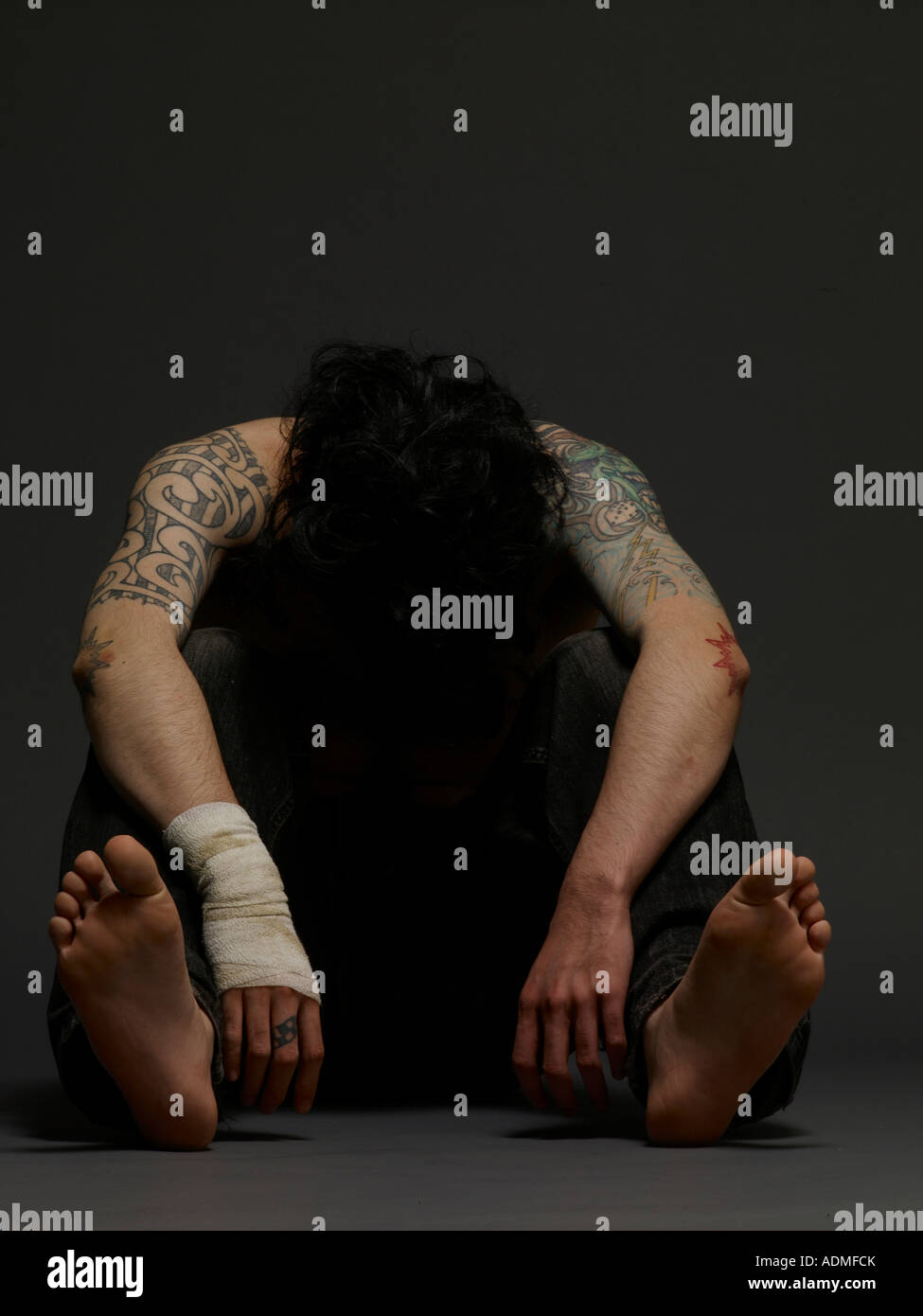 Young man sitting on floor with head down Stock Photo - Alamy