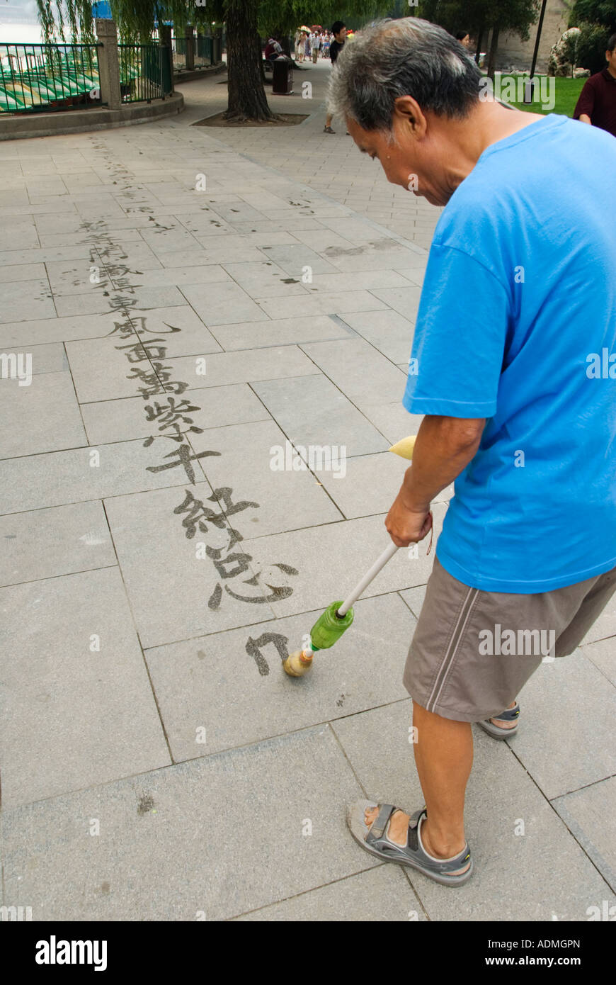Man writing Chinese calligraphy on ground with water brush in Beihai ...