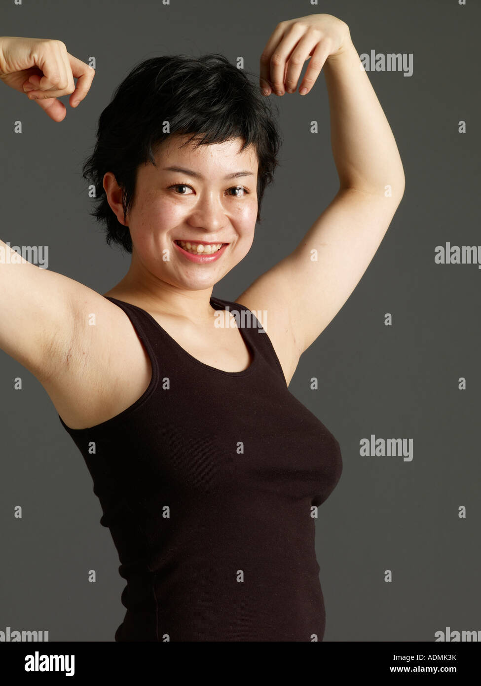 Woman flexing her muscles smiling Stock Photo - Alamy