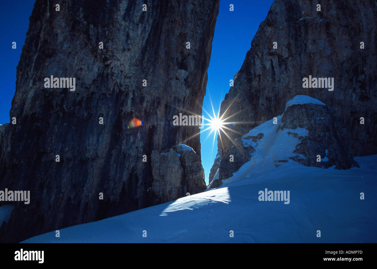 Cinque Torri in back light with the sun, rock walls in winter, blue sky ...