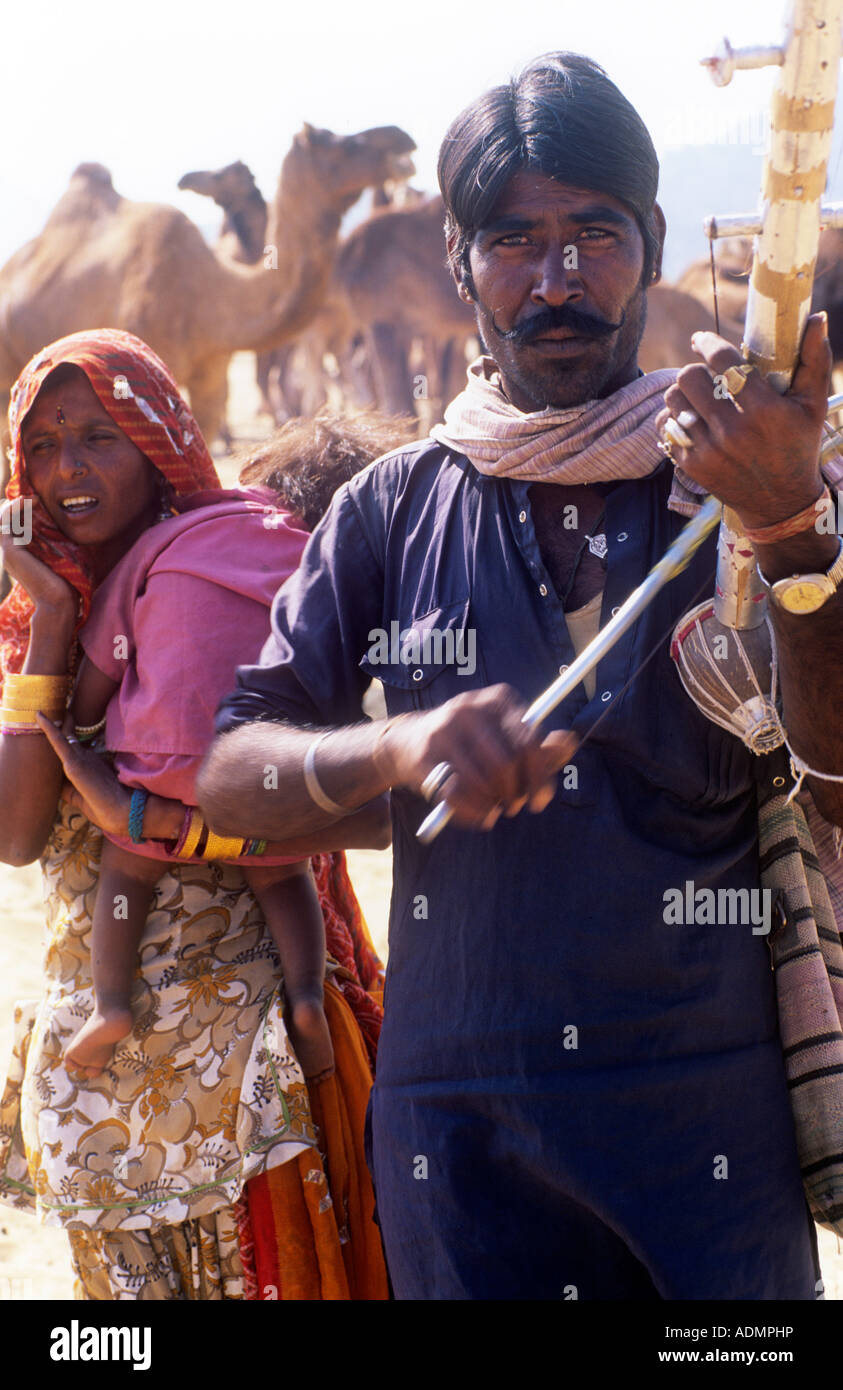 Musician playing a fiddle while his wife sings a folk song, Pushkar ...