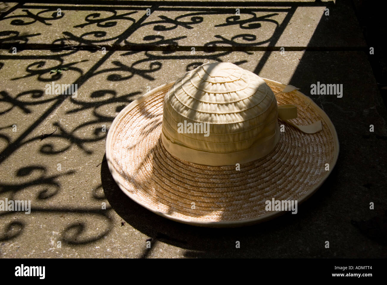 Straw hat in the shadow of a wrought iron gate Stock Photo - Alamy