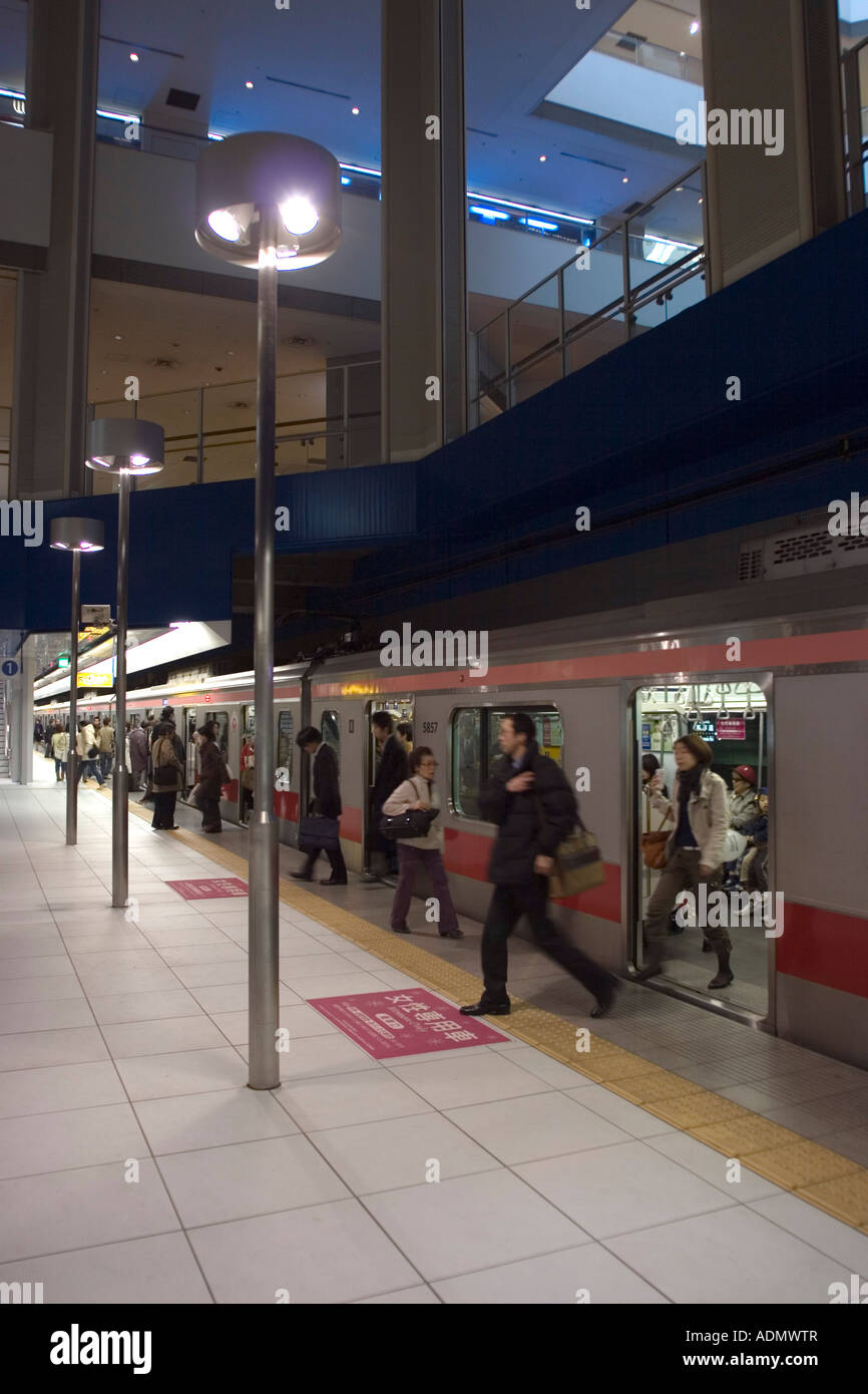 People stand on the platform at a subway station in Yokohama, Japan ...