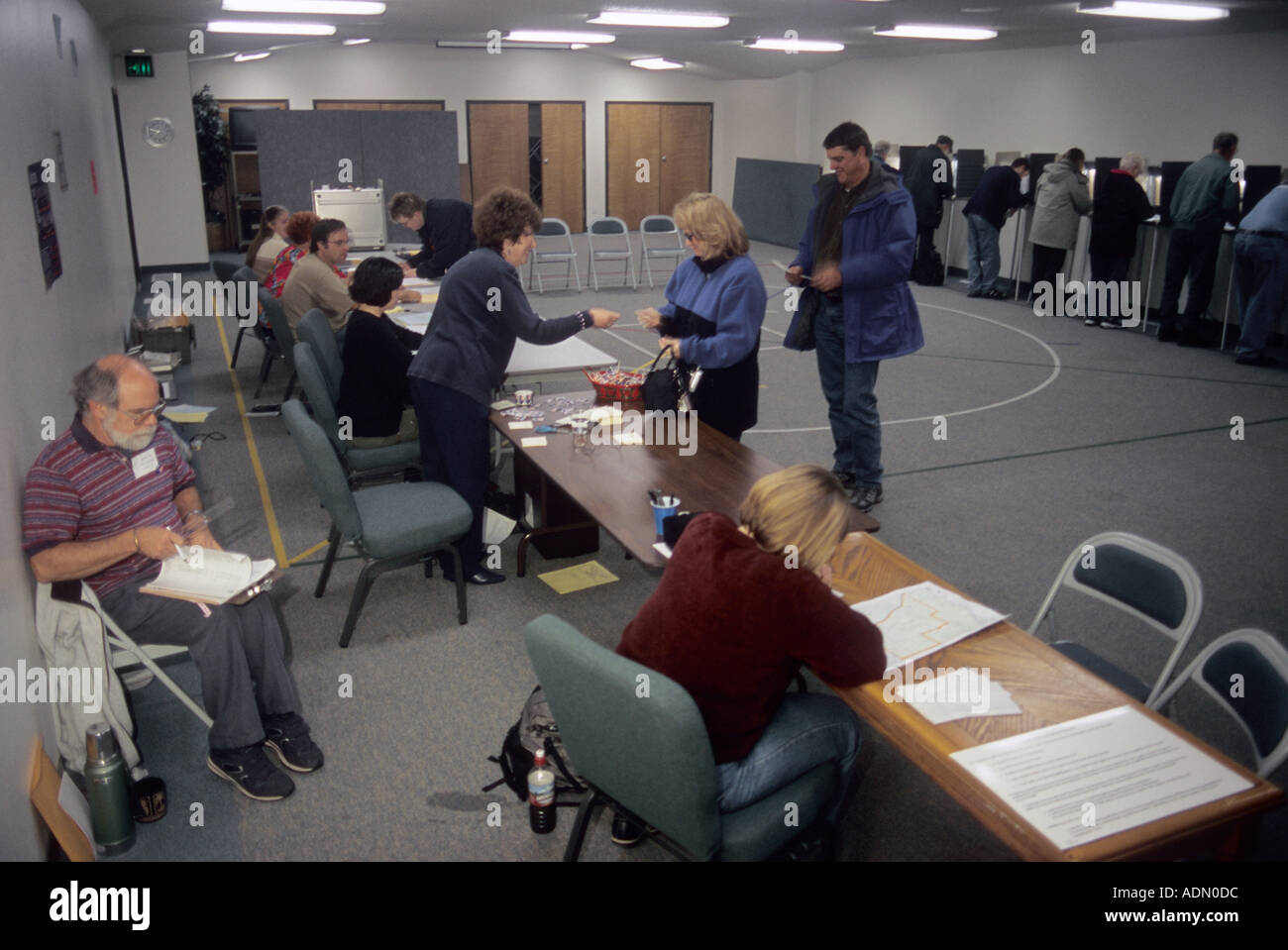 People in the voting booths and precinct workers at a polling station ...