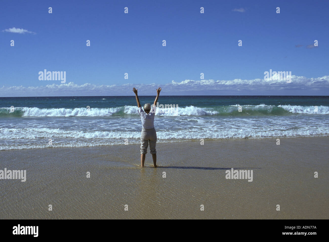 Mature woman wading in sea arms upraised MR available Stock Photo - Alamy