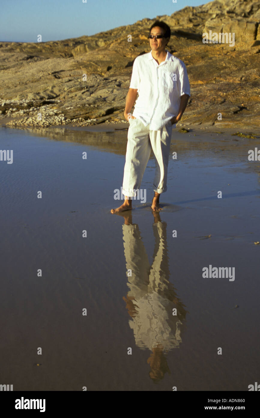 Australia Queensland man walking on beach near seaside rocks Stock ...