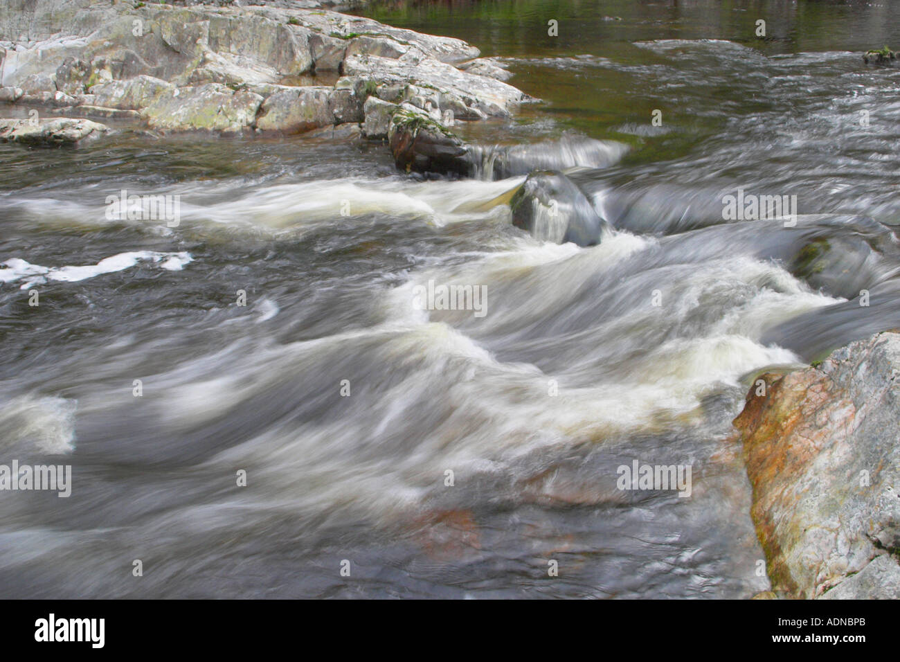 A slow shutter speed of river water flowing over the rocks giving the ...
