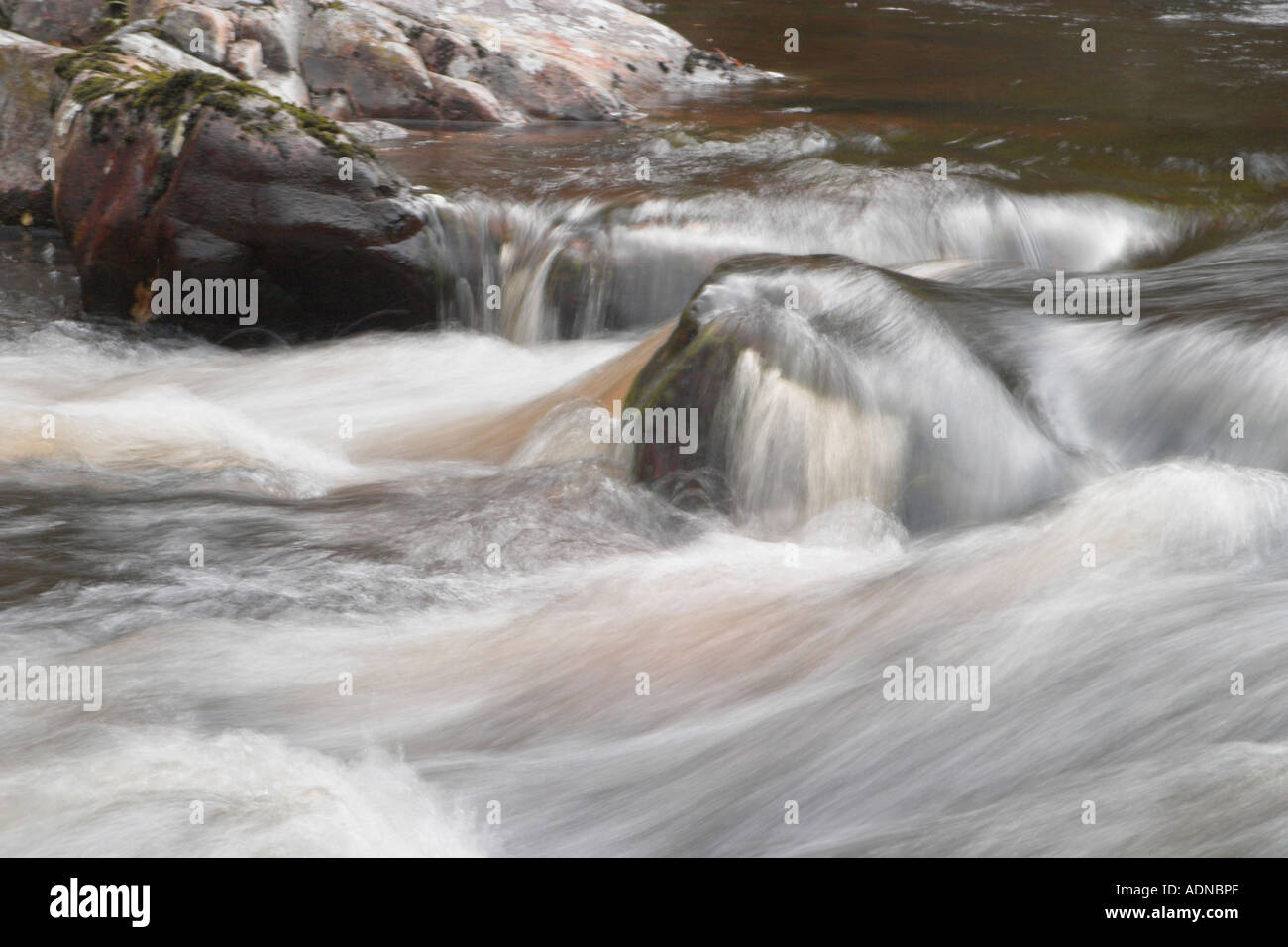 A slow shutter speed of river water flowing over the rocks giving the ...