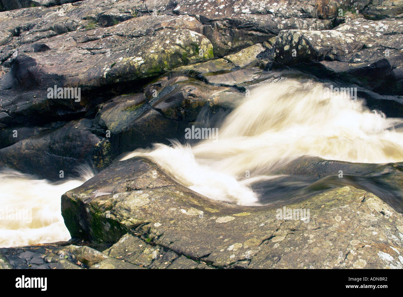 A slow shutter speed of river water flowing over the rocks giving the ...