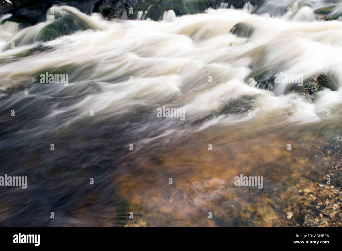 A slow shutter speed of river water flowing over the rocks giving the ...