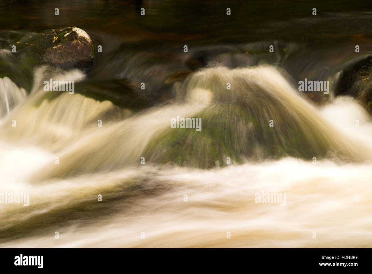 A slow shutter speed of river water flowing over the rocks giving the ...
