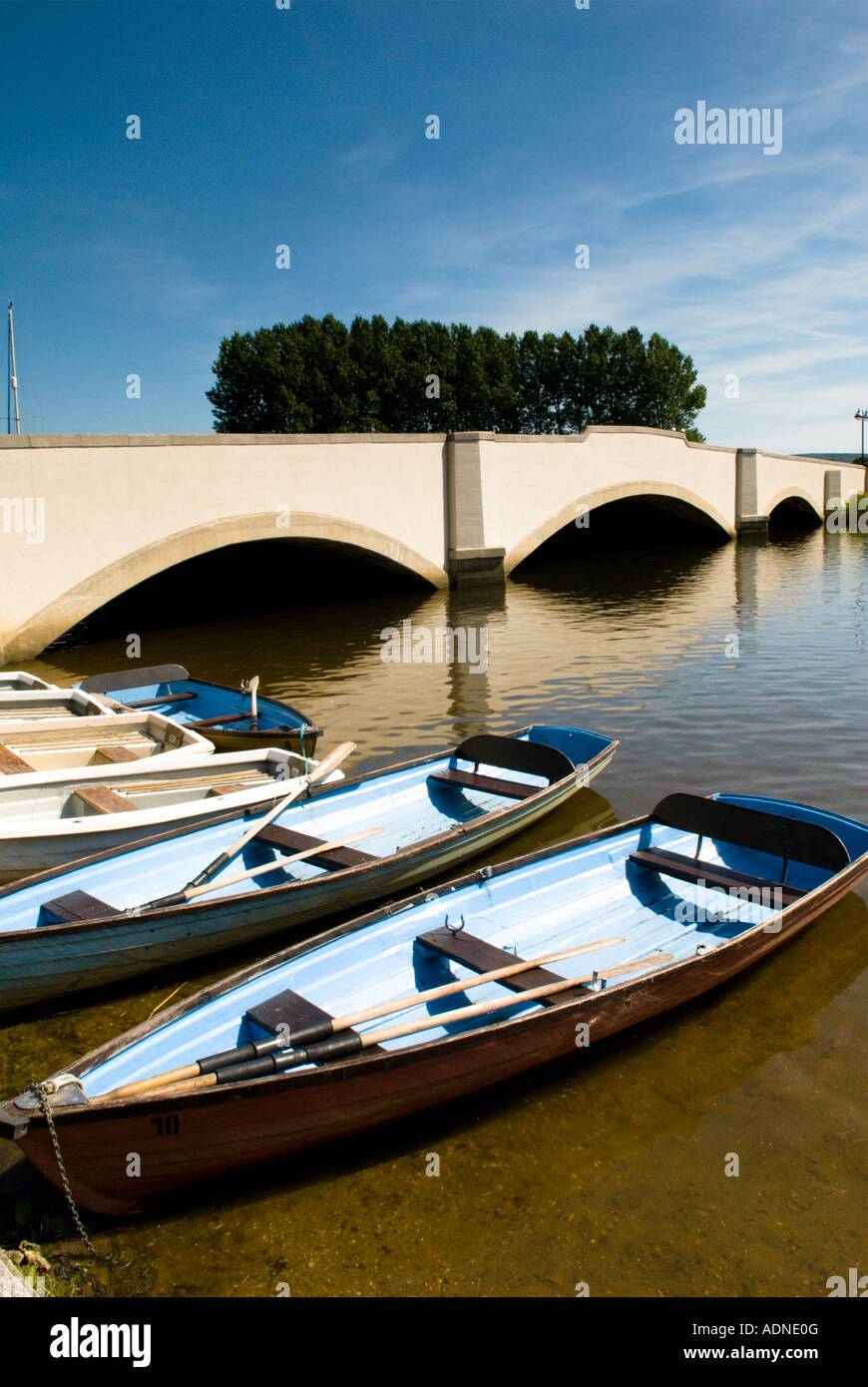Moored rowing boats by river bridge Stock Photo - Alamy