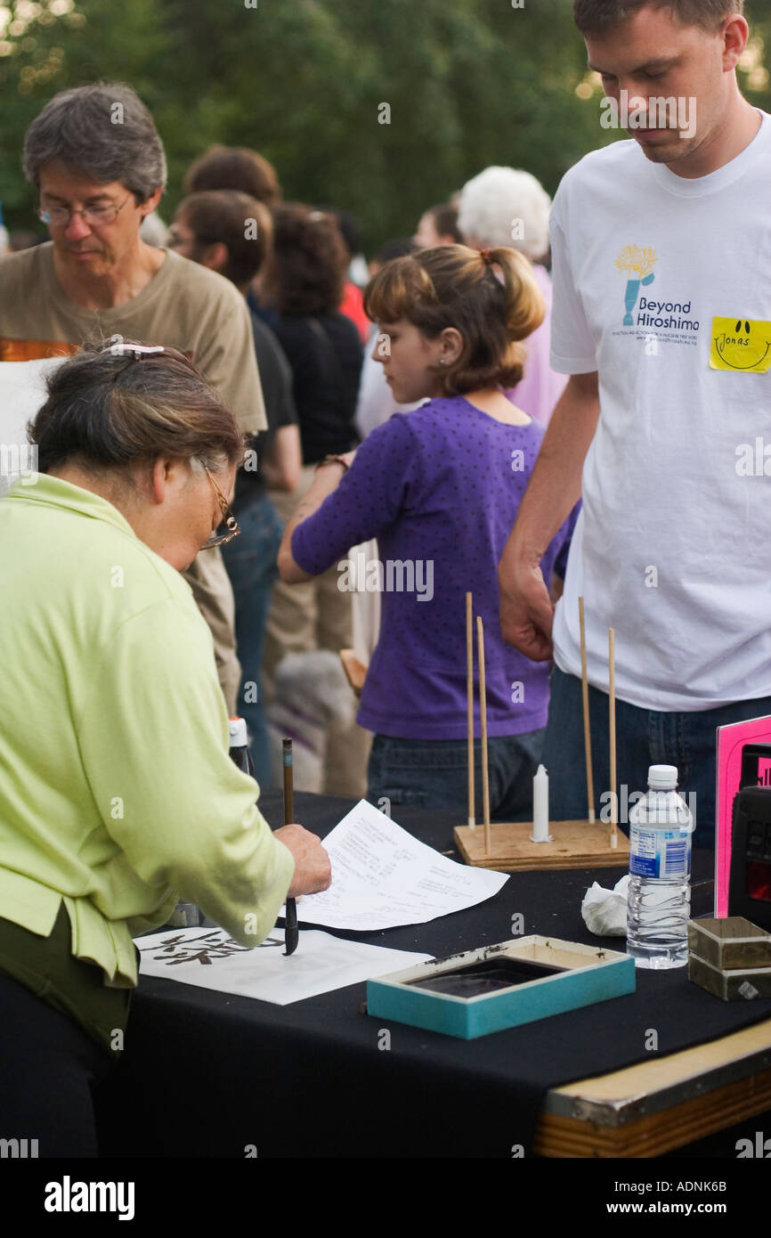People painting Japanese script symbols on paper coverings of lanterns ...