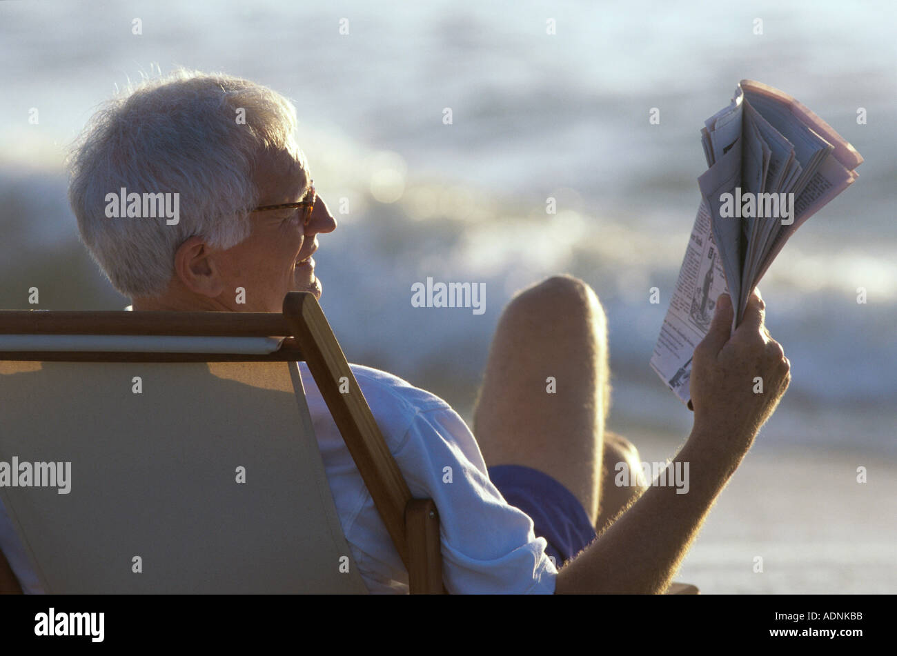 Rear view of a senior man reading a newspaper on the beach Stock Photo ...