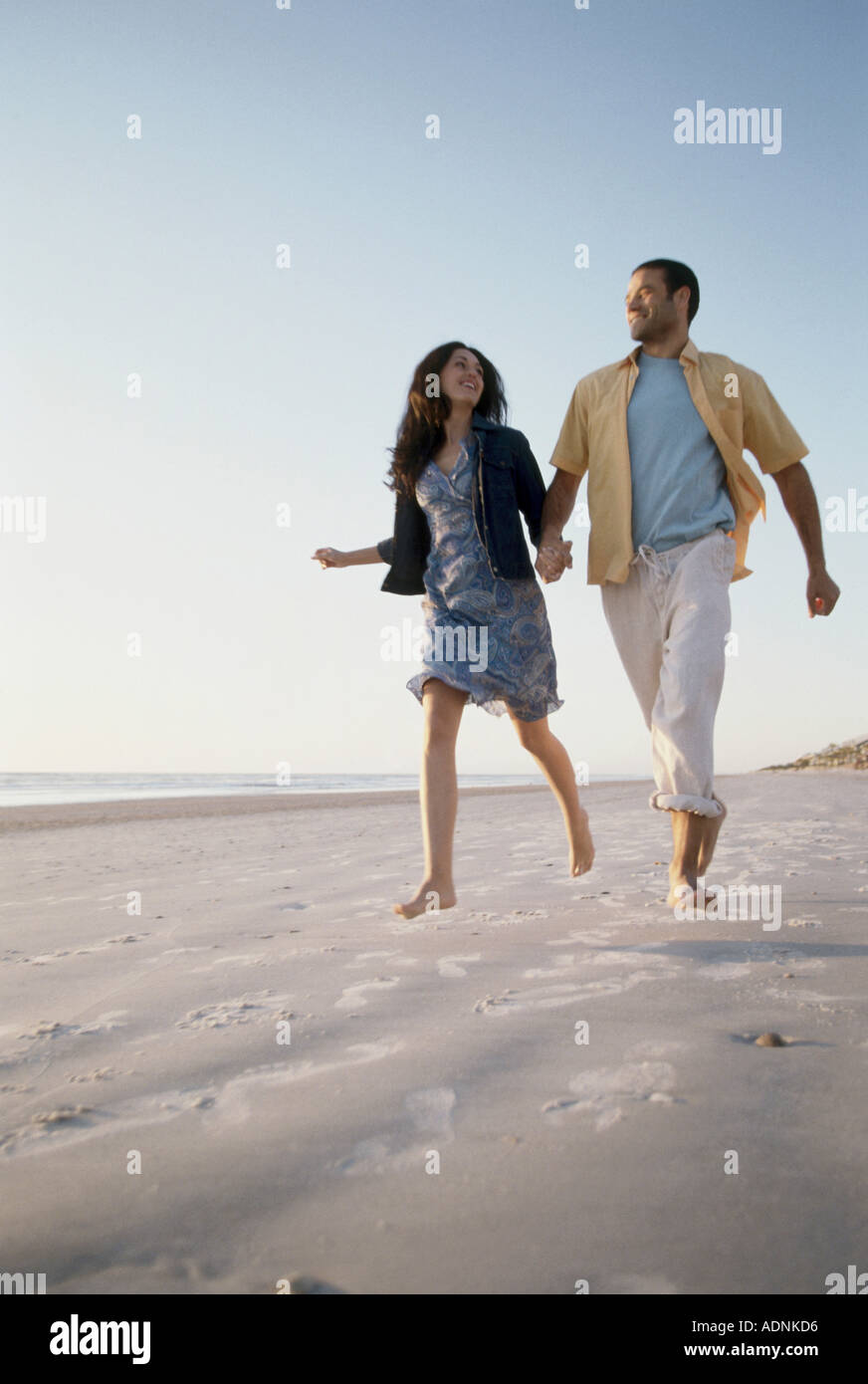 Low angle view of a young couple running together on the beach Stock ...