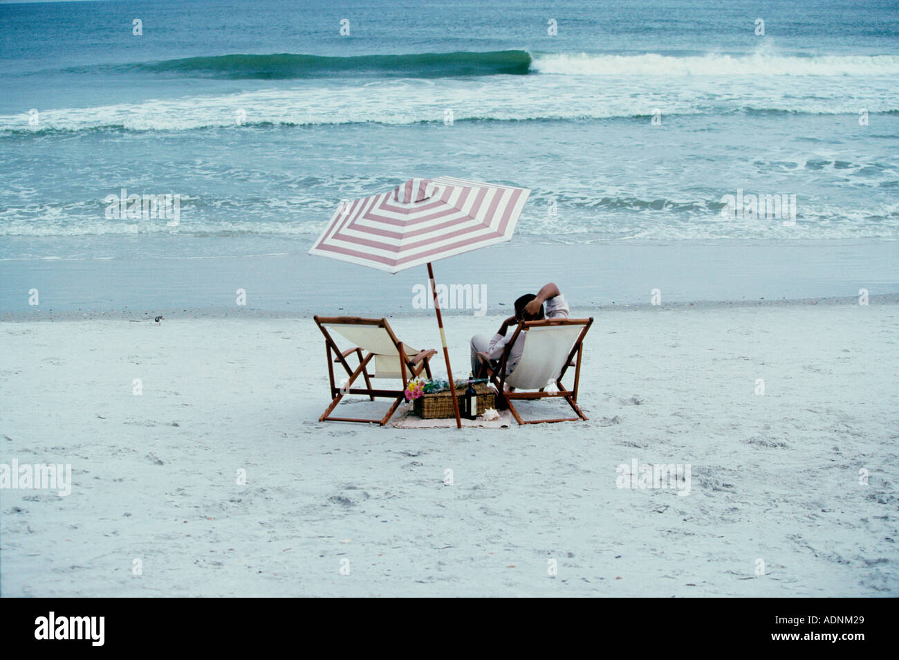 Rear view of a young man sitting on a deck chair on the beach Stock ...