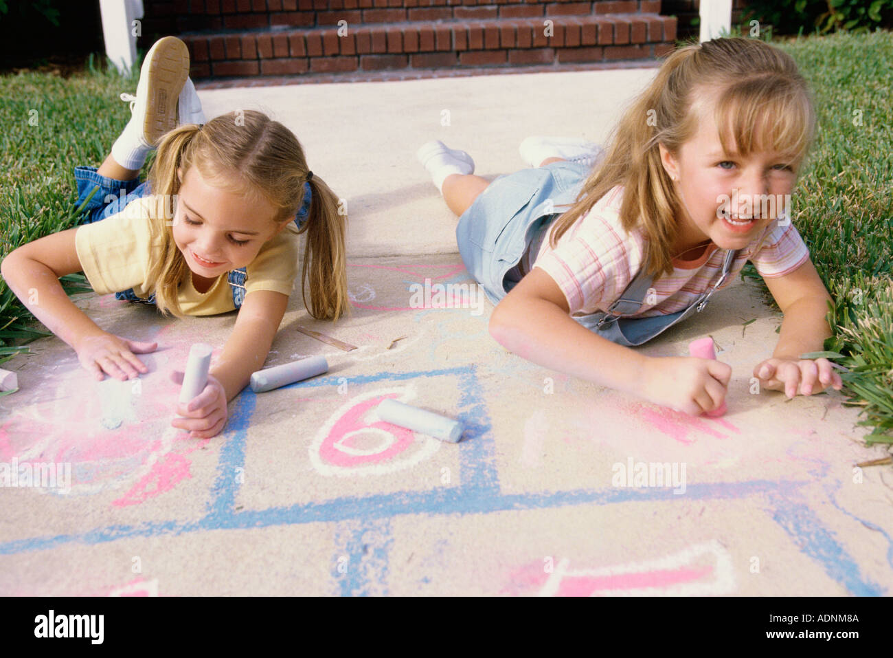 Portrait of two girls drawing on the ground with chalk Stock Photo - Alamy