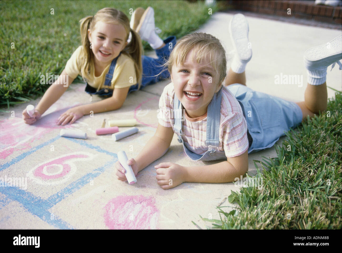 Portrait of two girls drawing on the ground with chalk Stock Photo - Alamy