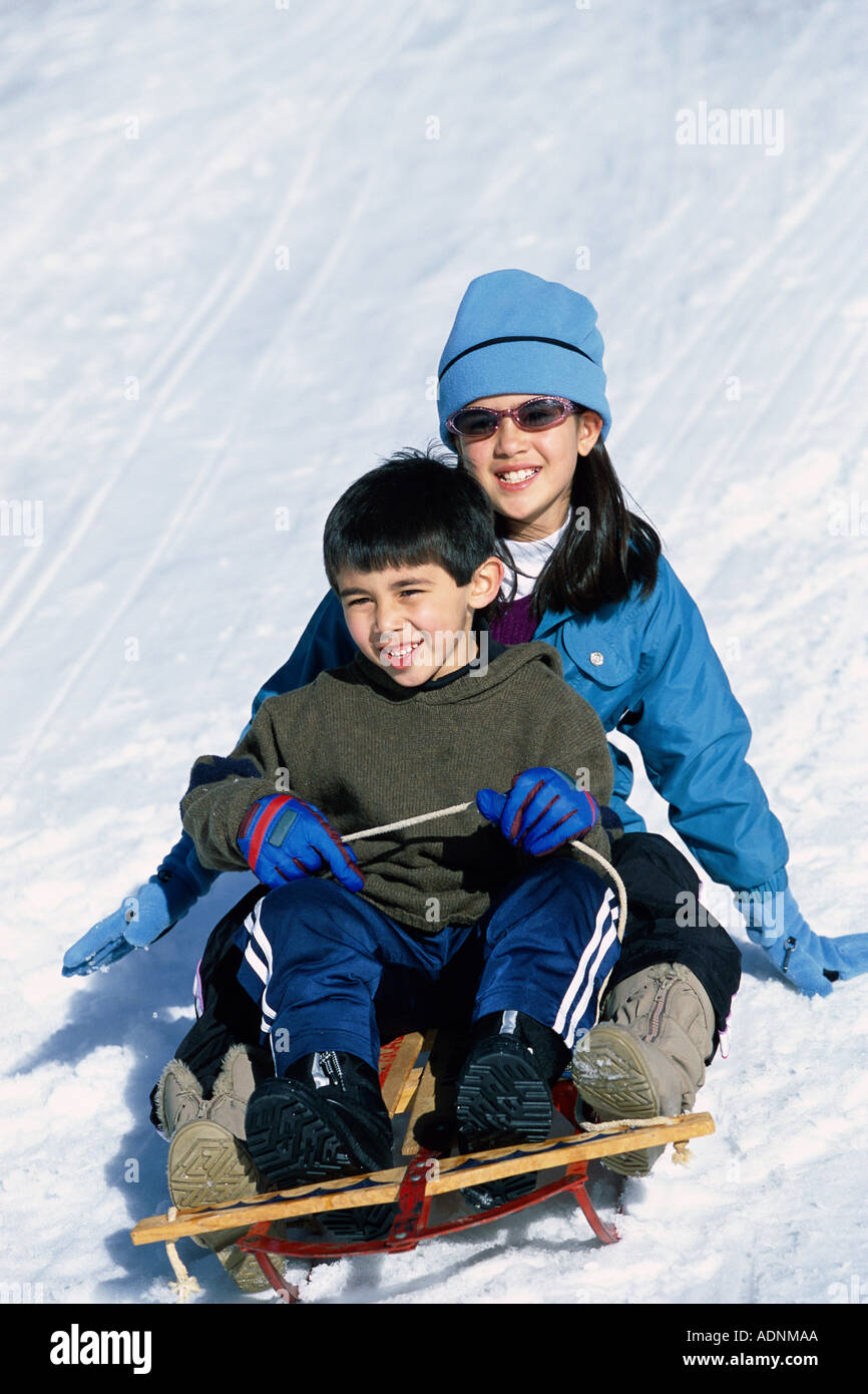 Boy and a girl riding a sled Stock Photo - Alamy