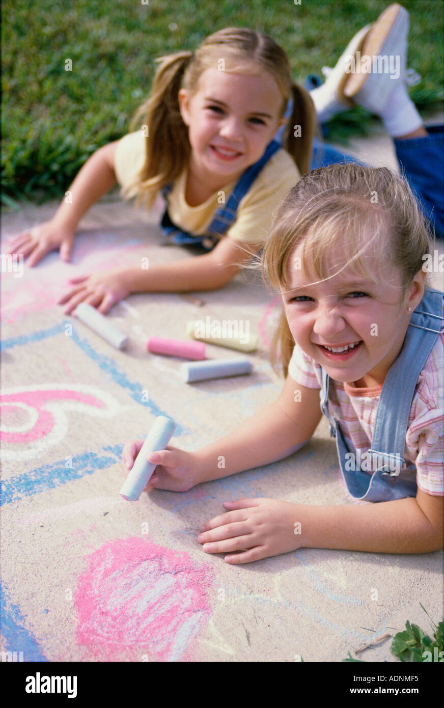 Portrait of two girls drawing on the ground with chalk Stock Photo - Alamy