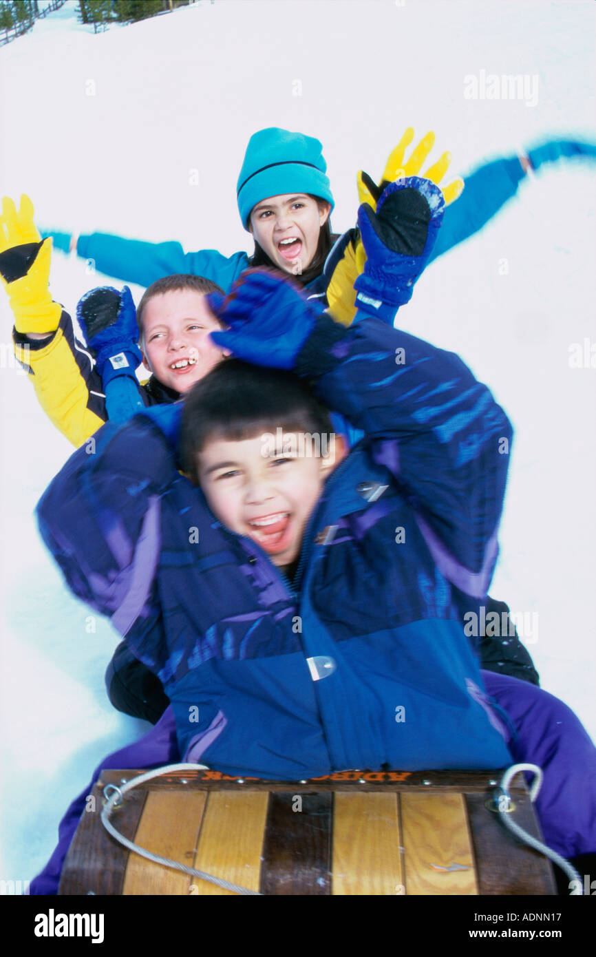 Two boys and a girl riding a sled Stock Photo - Alamy