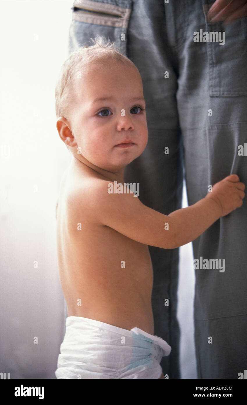 Little boy holding on to his parents legs Stock Photo - Alamy