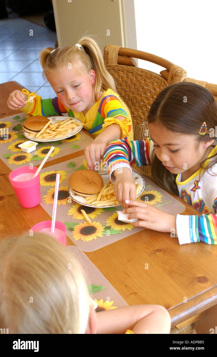 Three girls eating hamburgers Stock Photo - Alamy