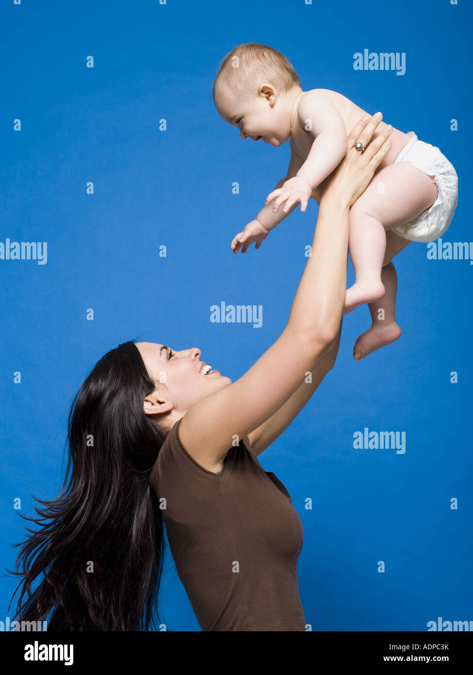 Woman lifting baby in air smiling Stock Photo - Alamy