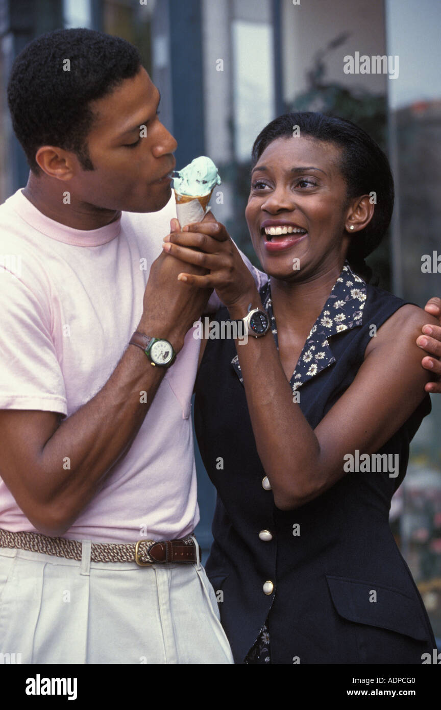 African American couple sharing ice cream cone Stock Photo - Alamy