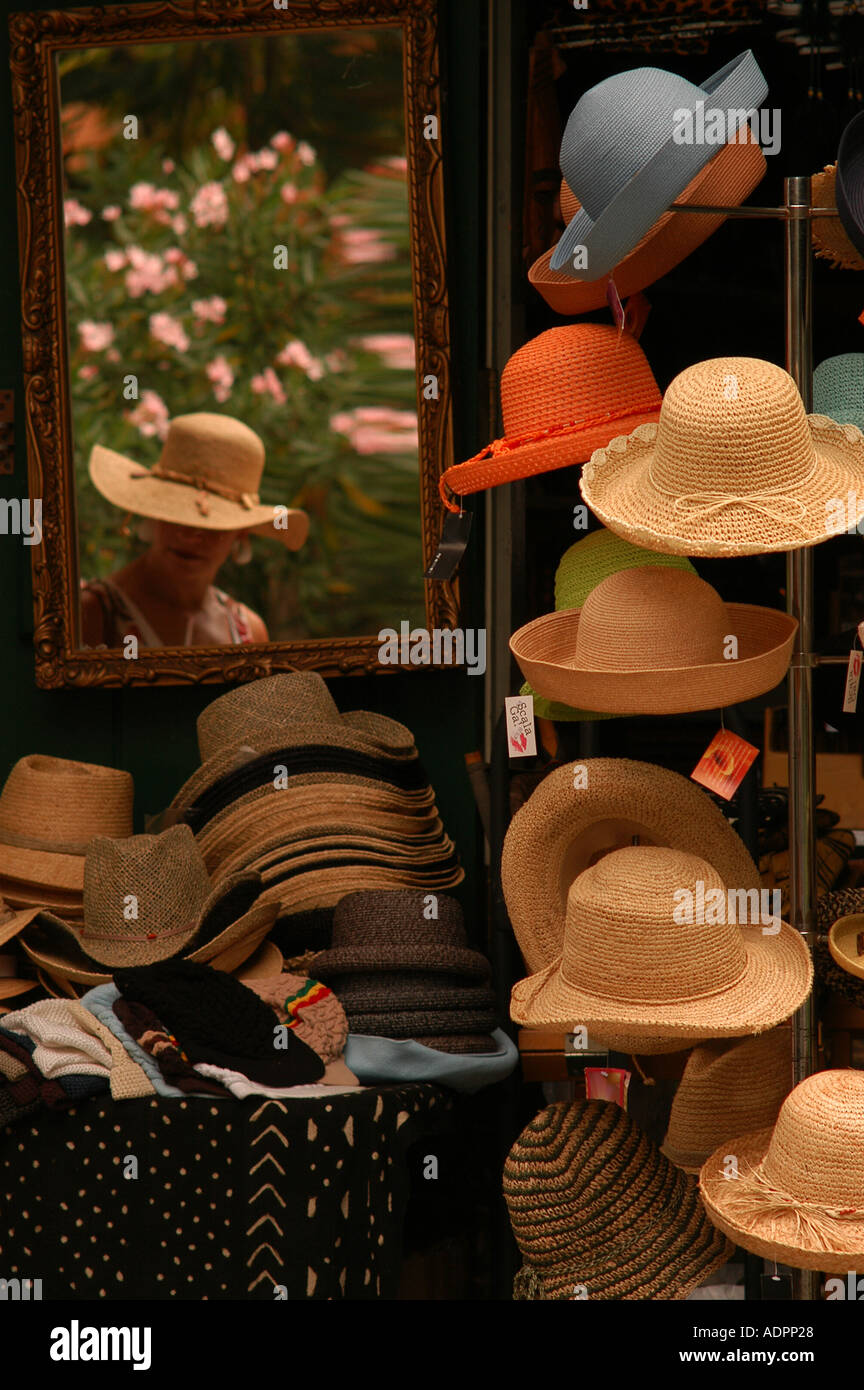 Hats on display with woman reflected in mirror in shop in French ...